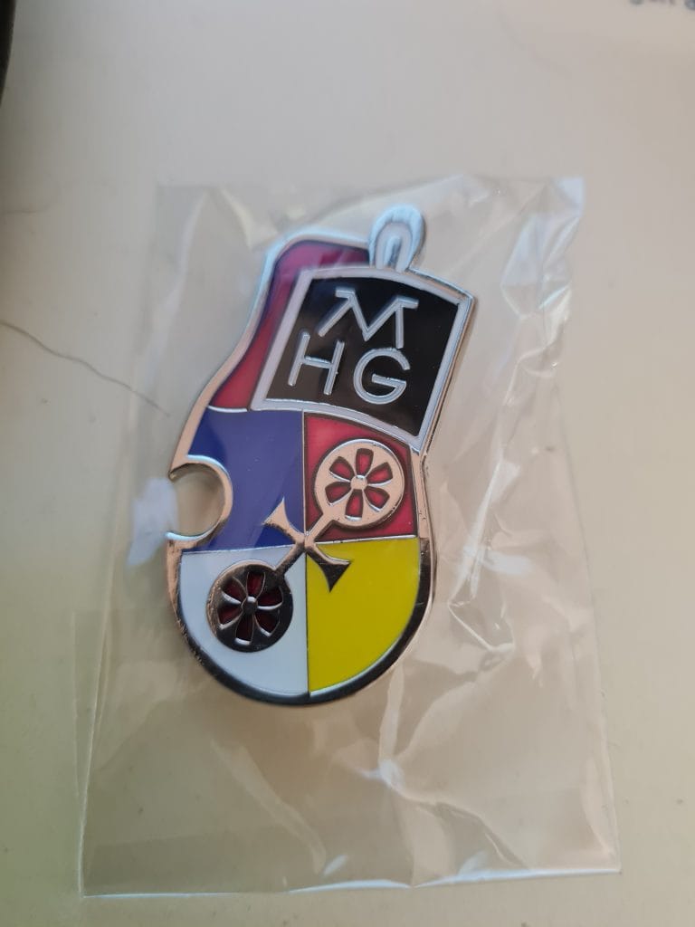 Logo der MHG als Pin | MHG-Shop